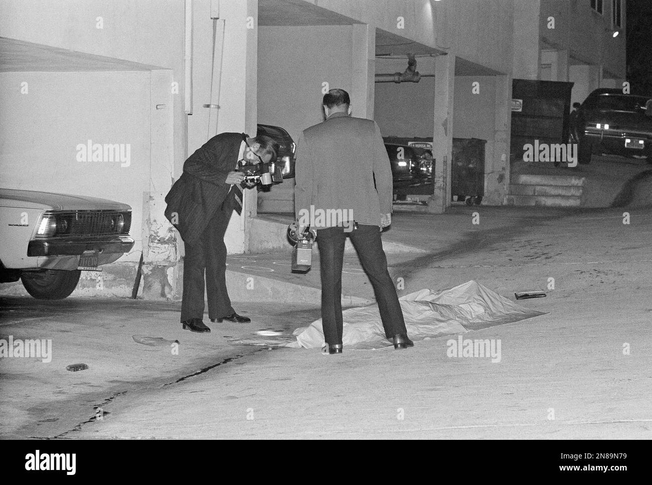Unidentified sheriff's deputies photograph the sheet-covered body of ...
