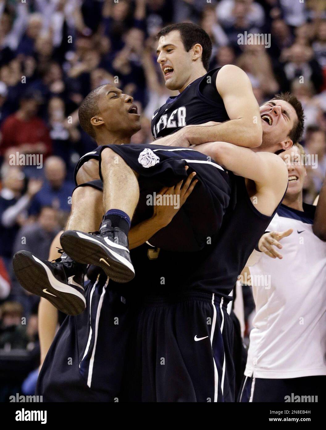 Butler guard Alex Barlow, center, is carried by forward Kameron Woods ...