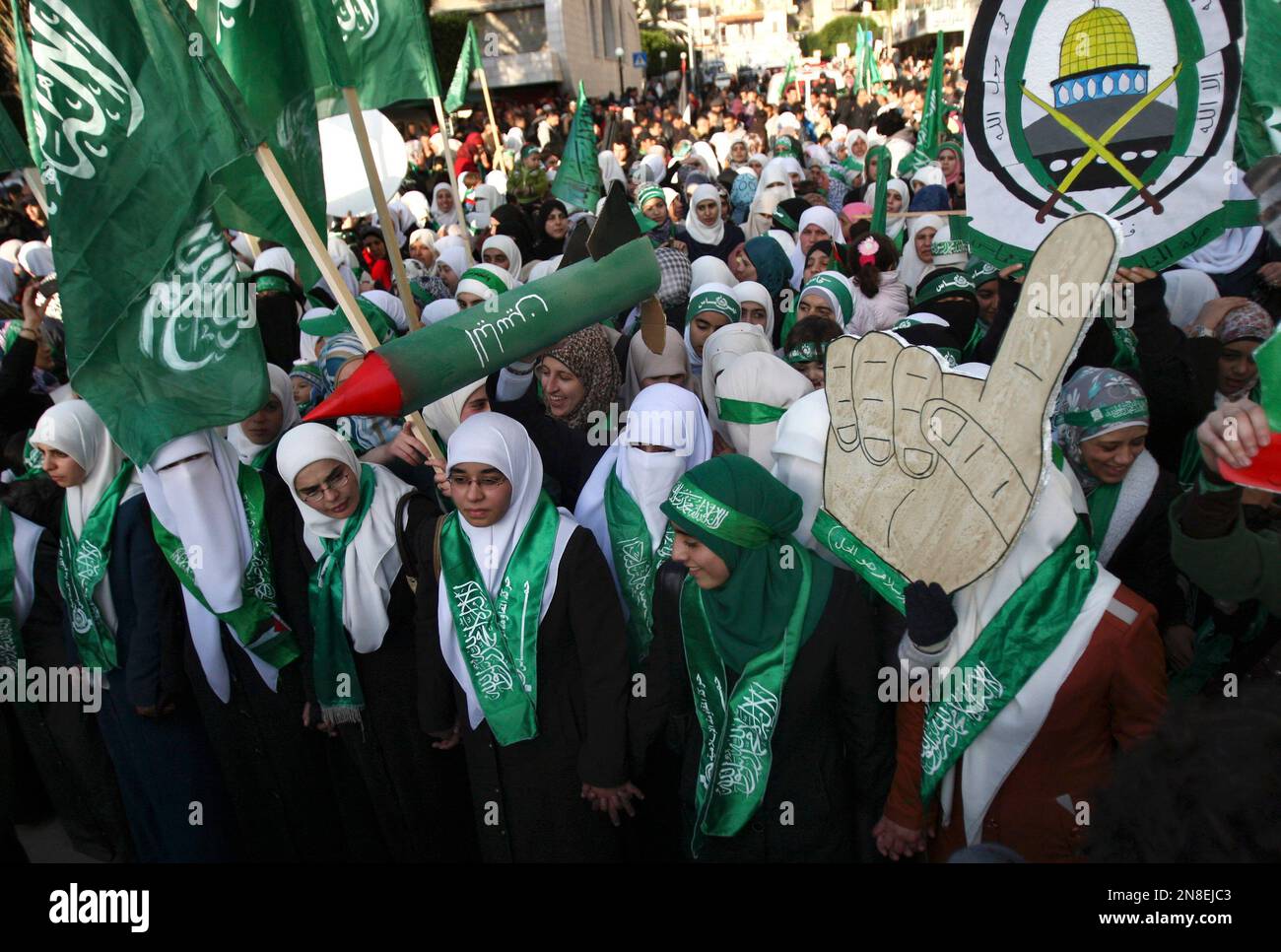 Palestinian supporters of Hamas hold signs and a model of a M75 long ...