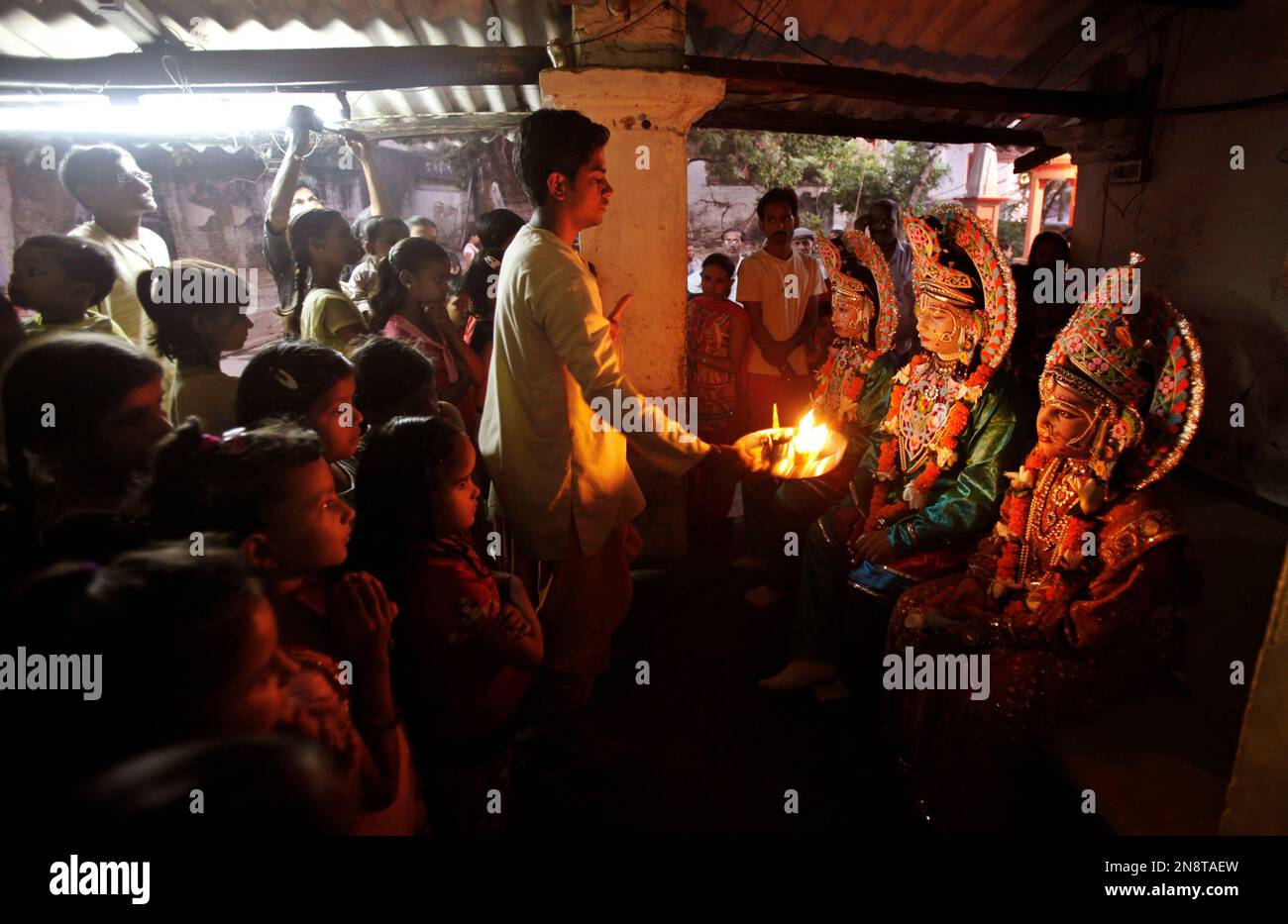 A Hindu devotee holds a traditional oil lamp as he offers prayers to ...