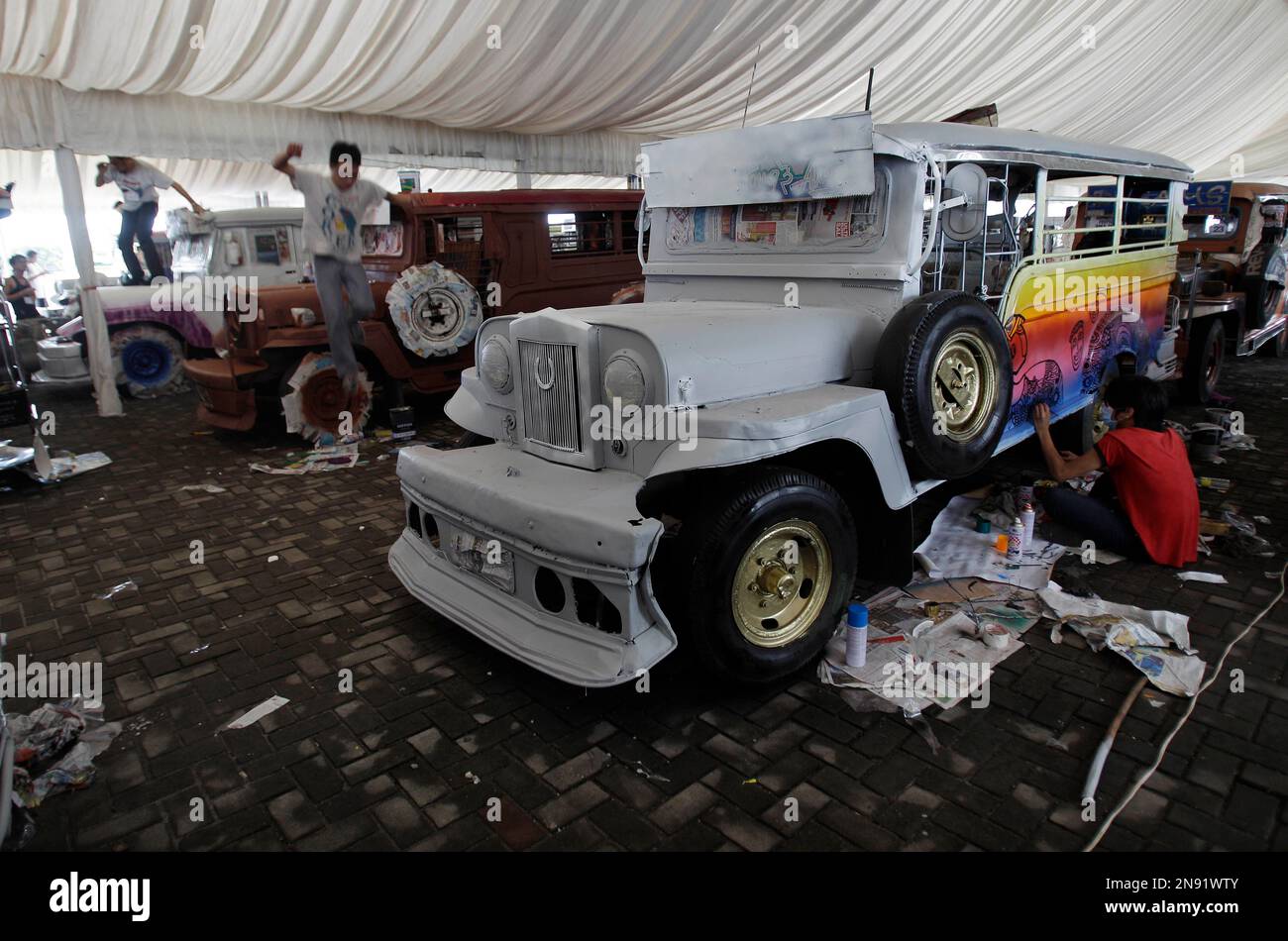 A Filipino student artist jumps off a passenger jeepney while another ...