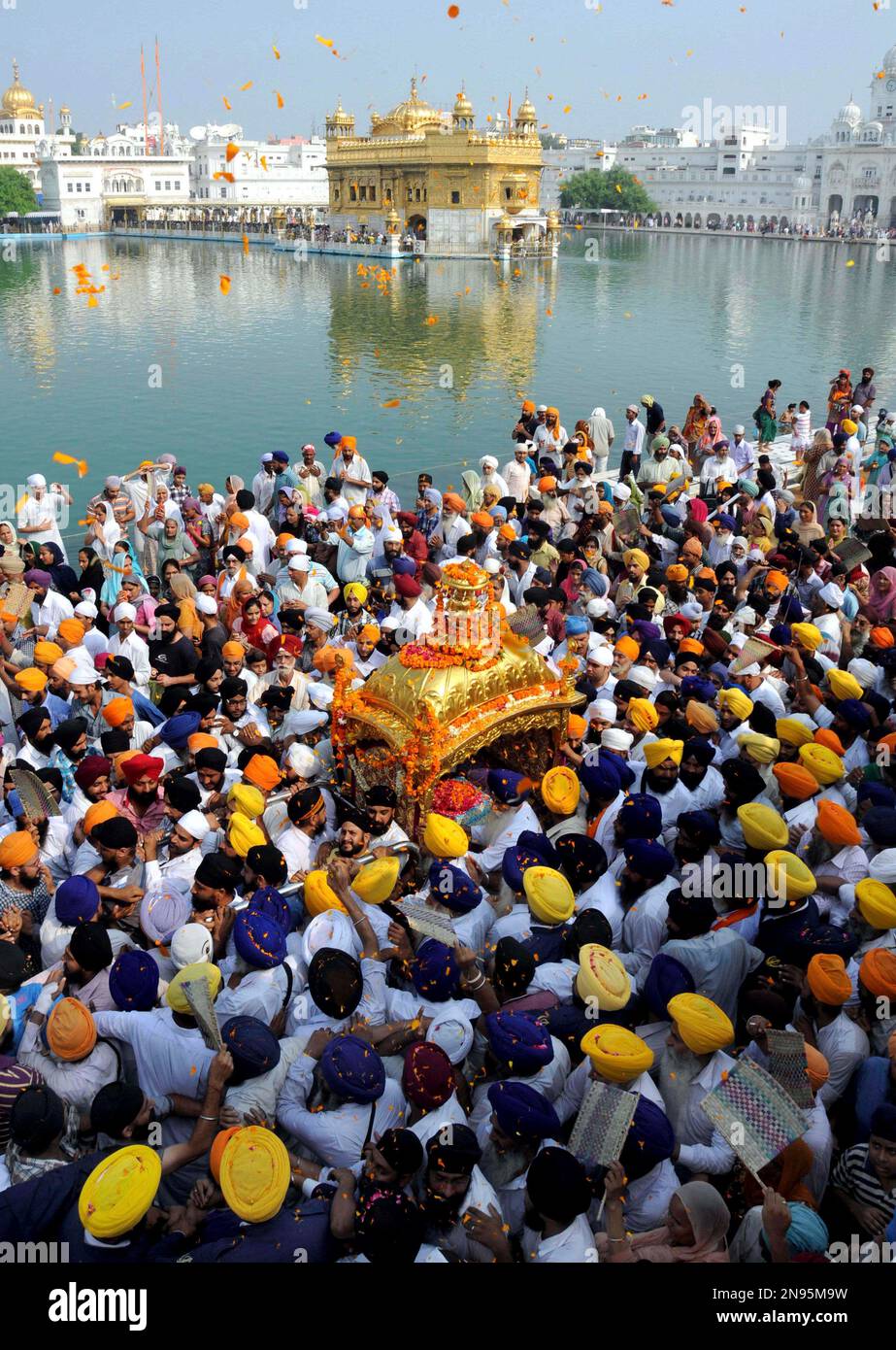 Sikh devotees crowd around a palanquin carrying the Guru Granth Sahib ...