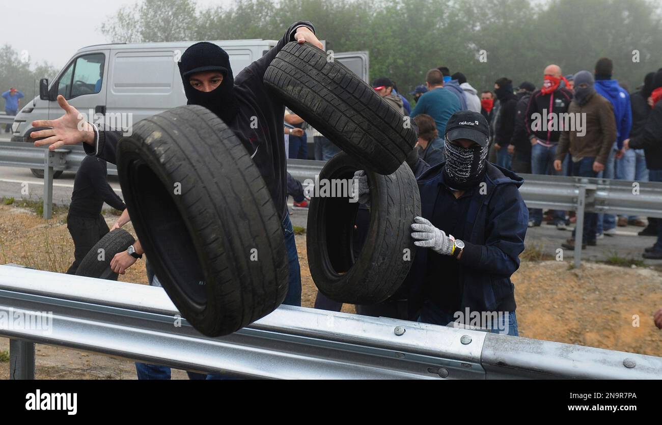 Miners on strike throw tires over a highway guard rail to build a ...
