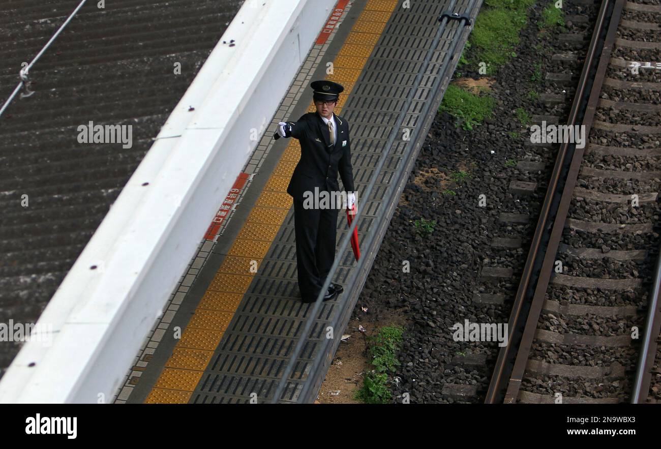 A station employee signals before the arrival of an incoming train at a ...