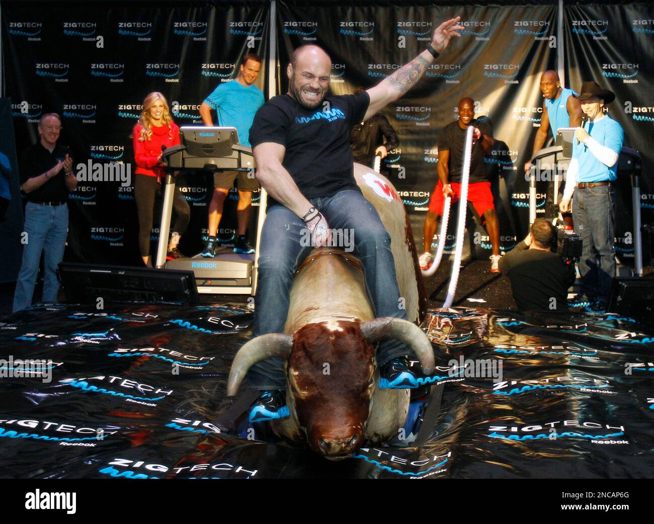 MMA champion Randy Couture, center, rides a mechanical bull during a ...