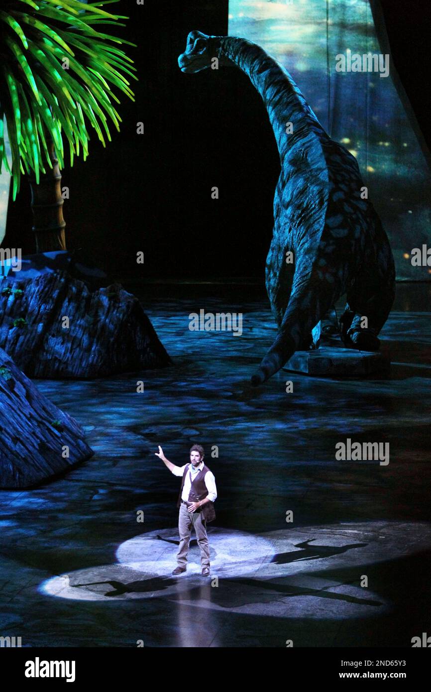 A paleontologist character narrates a scene in front of a massive life ...