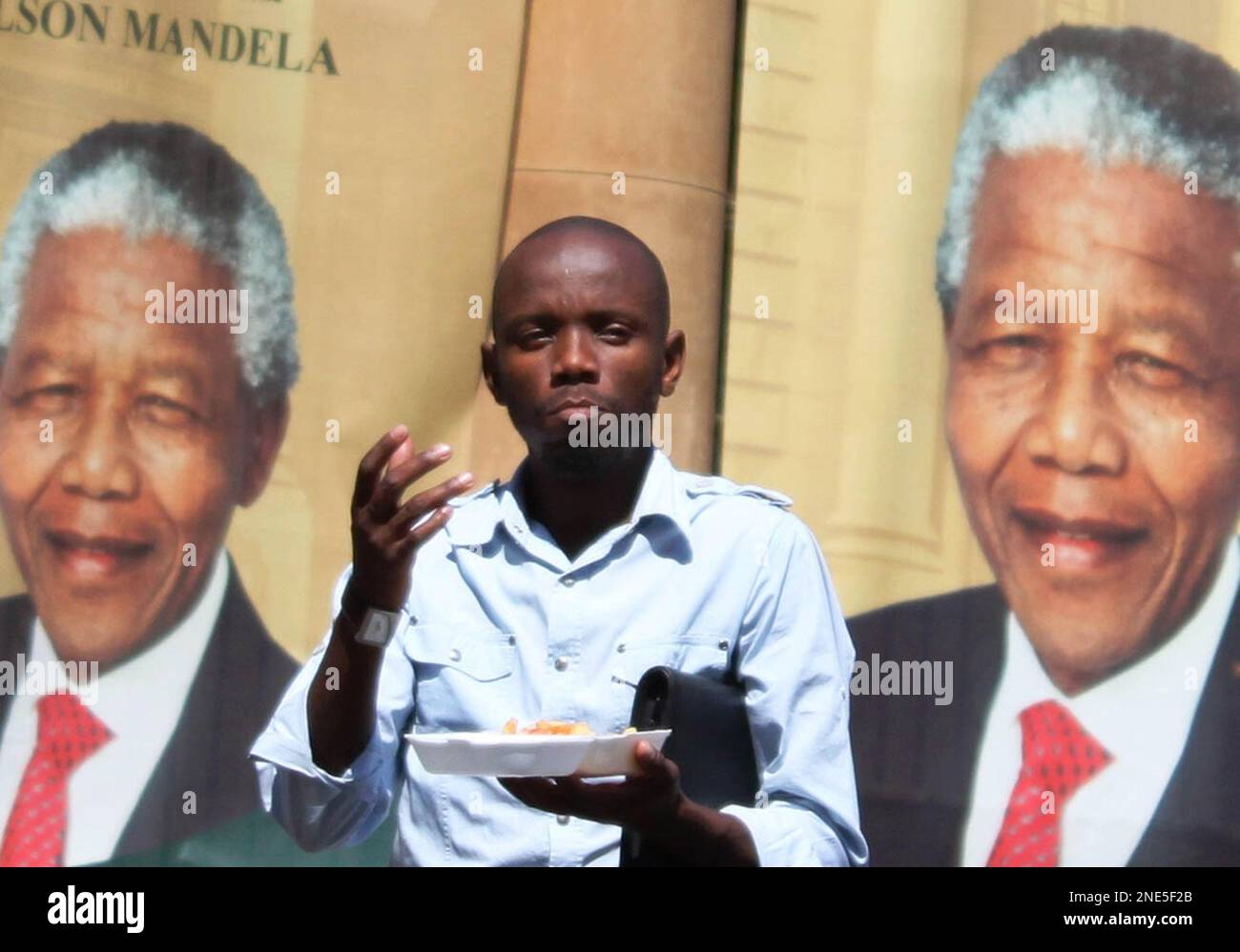 A pedestrian walks past portraits of former President Nelson Mandela in ...