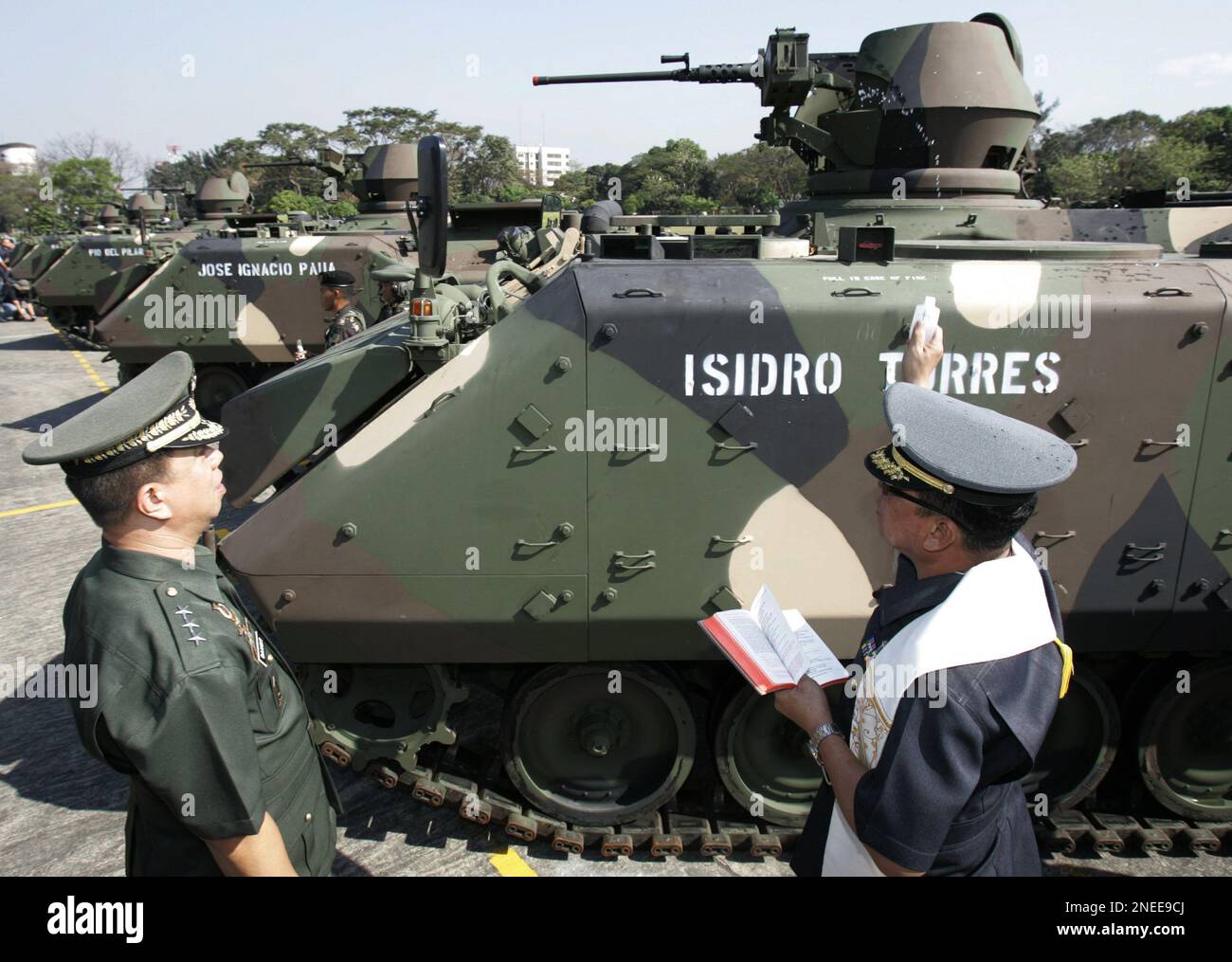 A military chaplain sprinkles holy water during blessing rites of newly ...