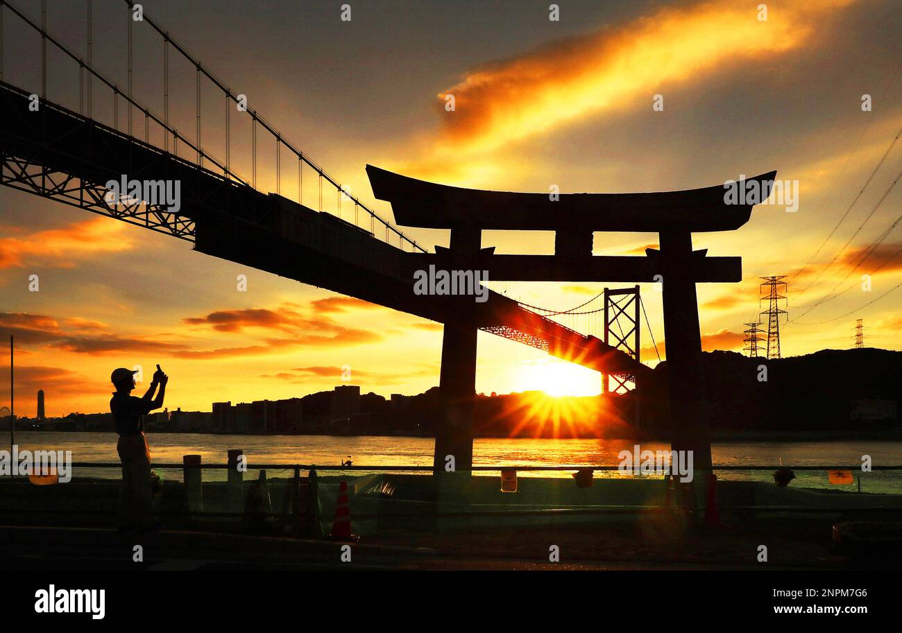 A photo shows a sunset over the Kanmon Bridge and the entrance gate of ...