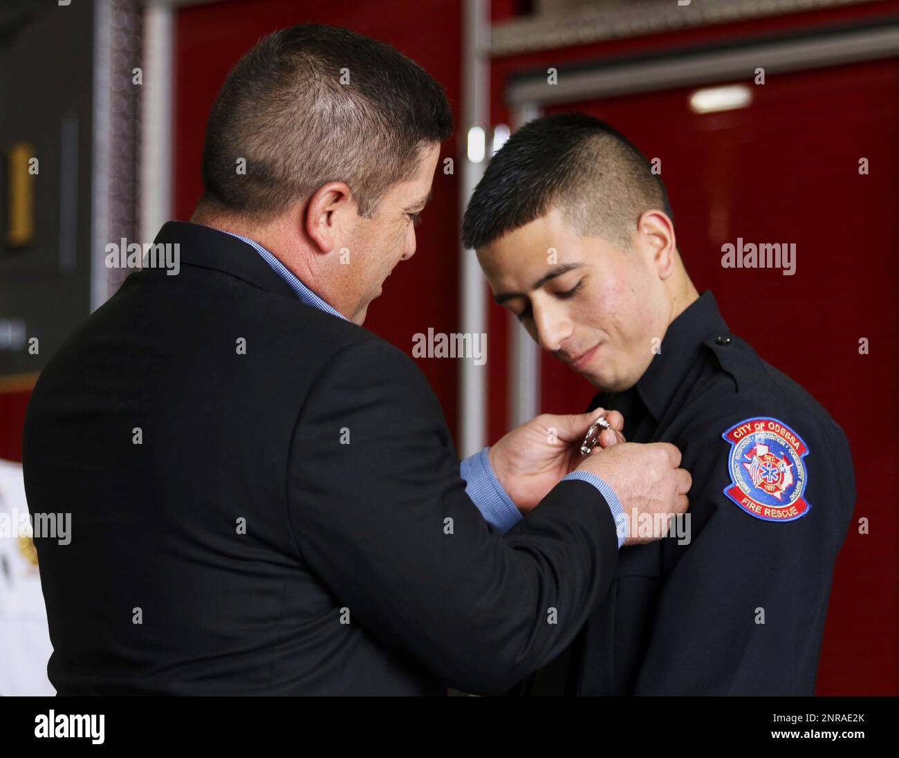 David Castillo, left, a firefighter in Midland, pins a badge on his son ...