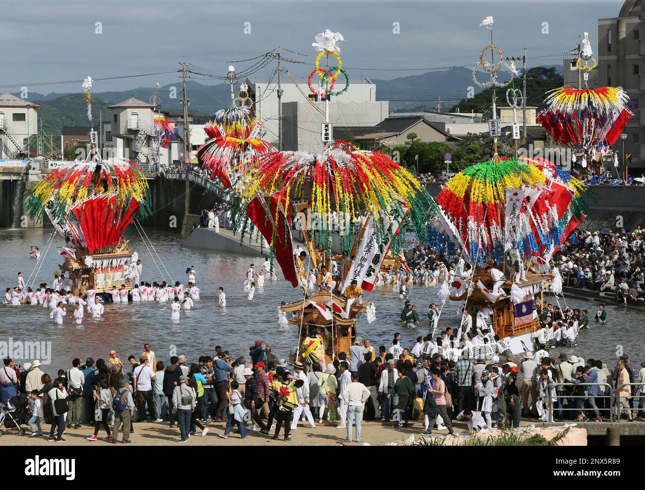 People carry colorfully decorated Yamagasa and cross Hikoyama River ...