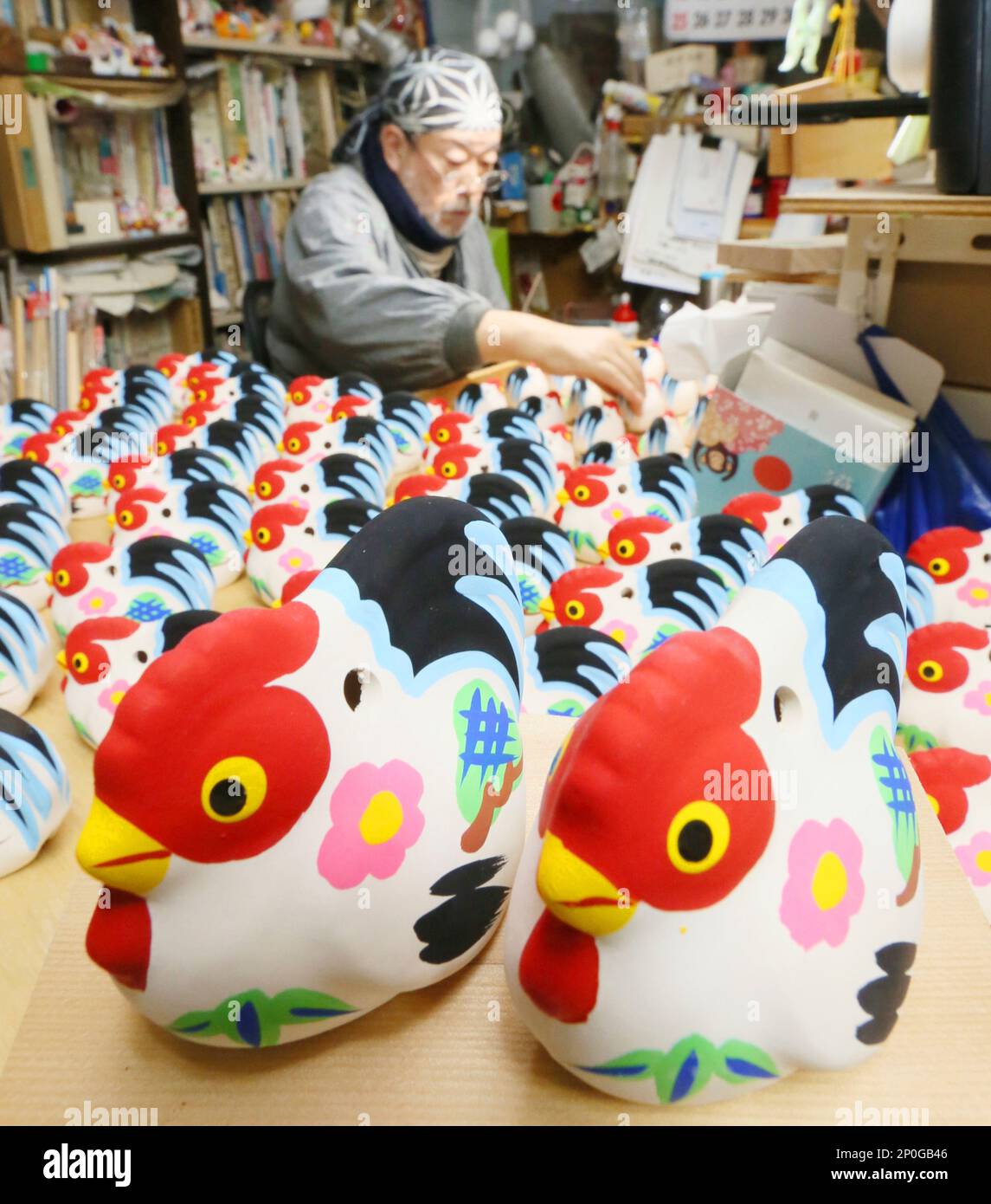 A craftsman adds the finishing touches to rooster-shaped clay bells at ...