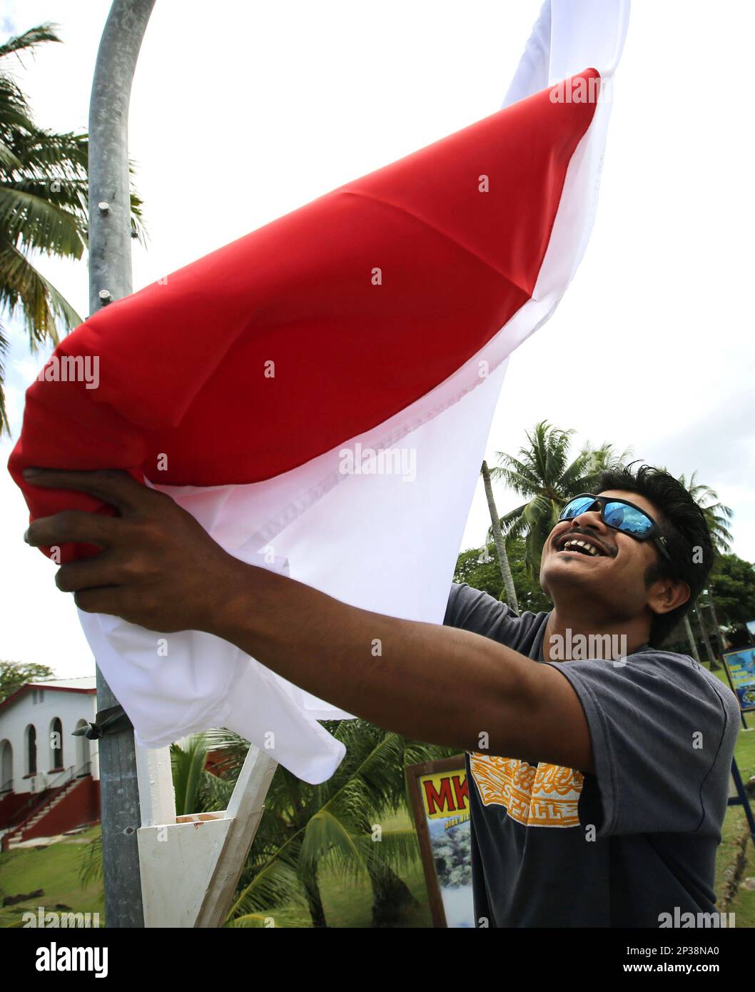 A local man prepares to set up a Japanese national flag, a hinomaru to ...
