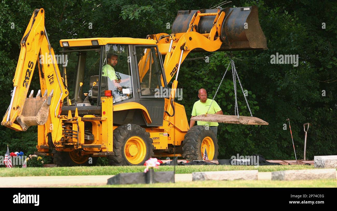 Workers Lenny Reynolds Jr., left, and Josh Goad return the lid back ...