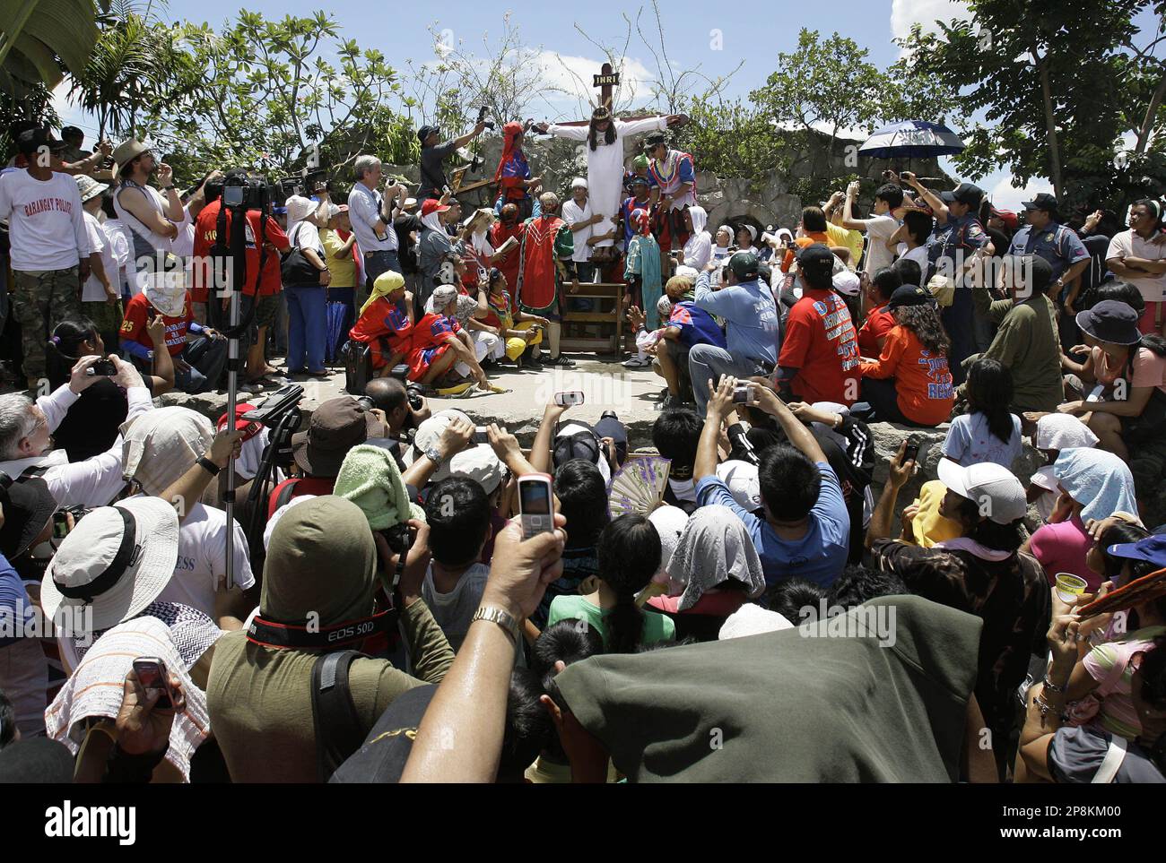 Filipino devotees watch as a penitent is nailed to the cross during ...