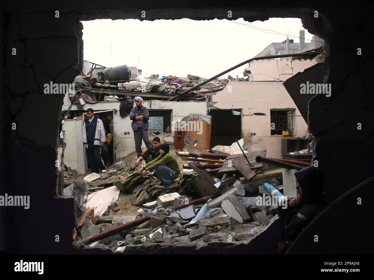 Palestinians search in the rubble of a destroyed house after an Israeli ...