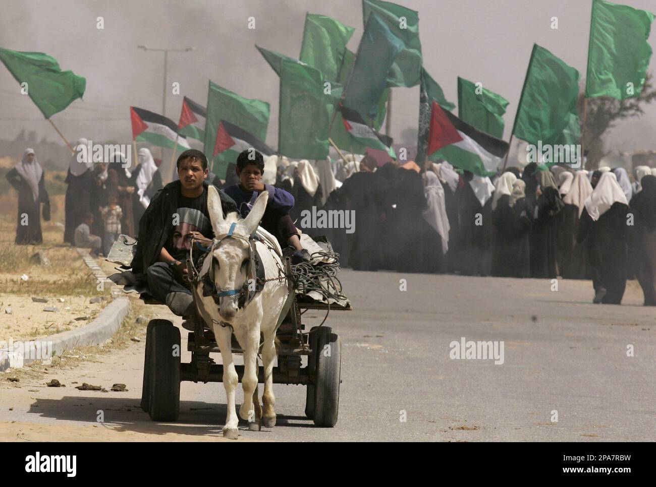 Palestinians ride on a donkey cart in front of women and children as ...