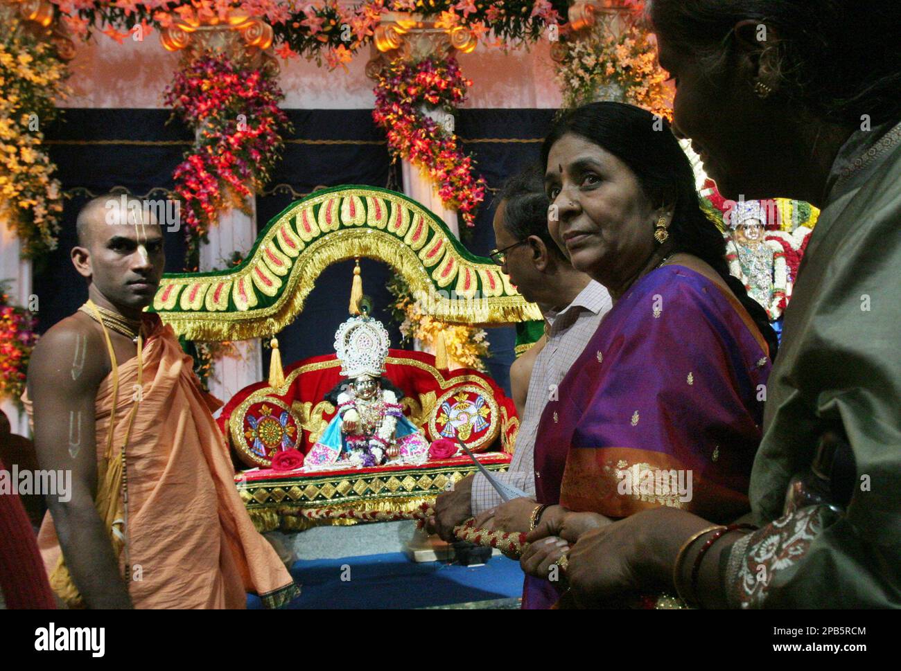 Hindu devotees hold on to a rope, tied to the cradle in which an idol ...
