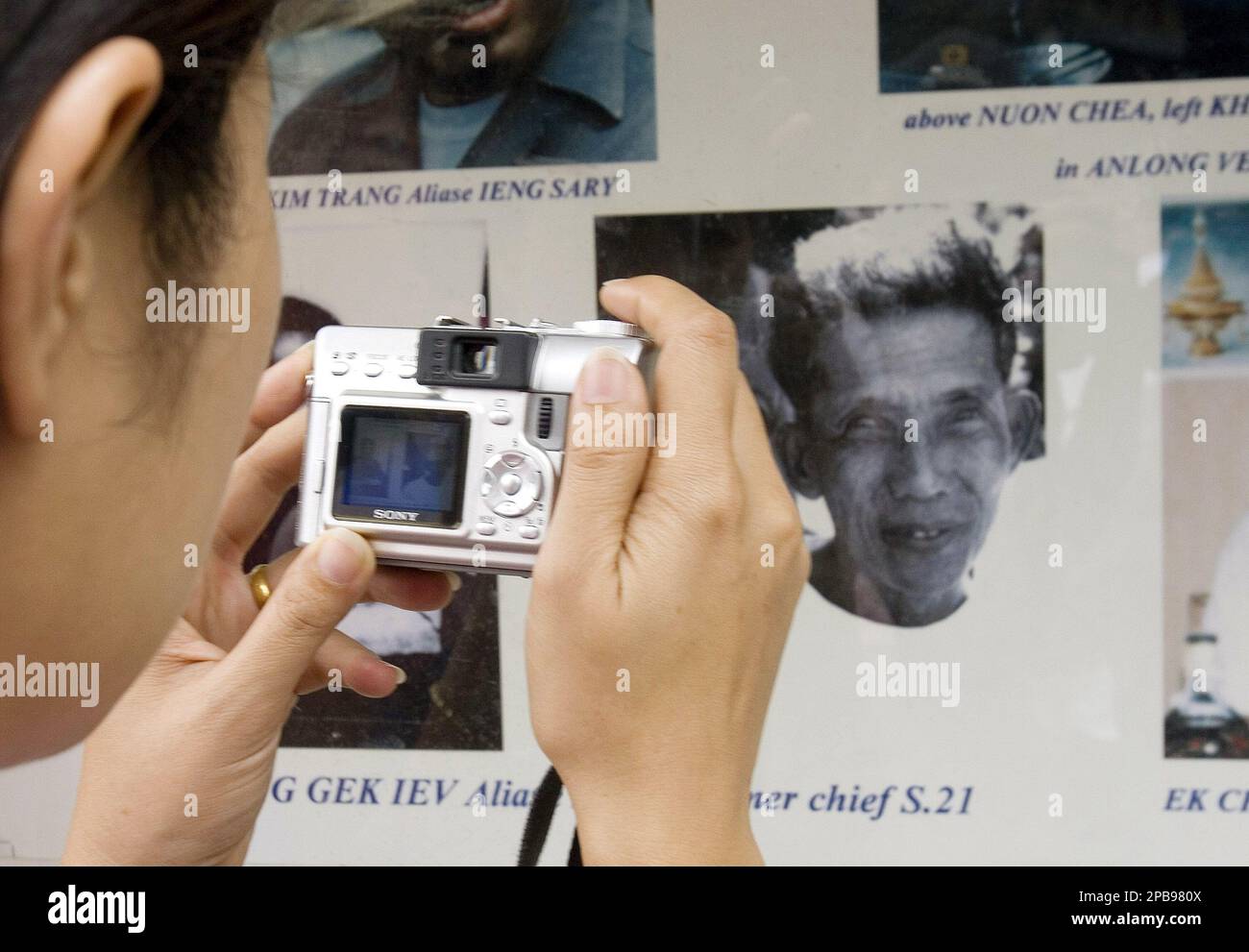 A woman aims her camera to take pictures of a photograph of Kaing Guek ...
