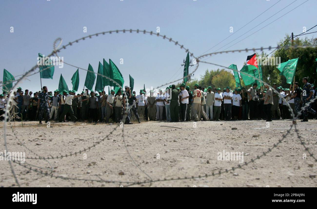 Palestinian supporters of Hamas stand behind razor-wire on the ...