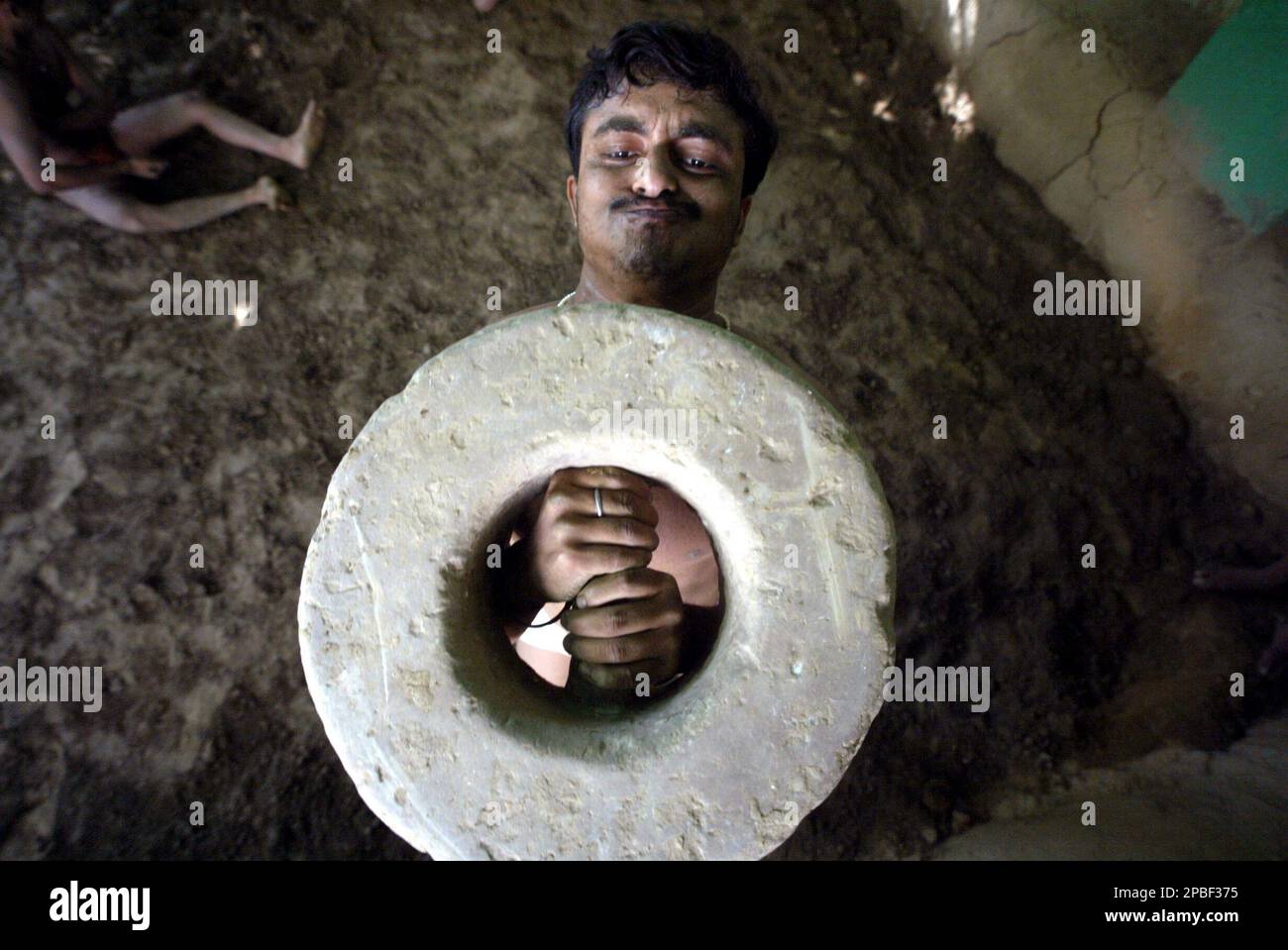 An Indian traditional wrestler exercises with a stone ring in an akhada ...