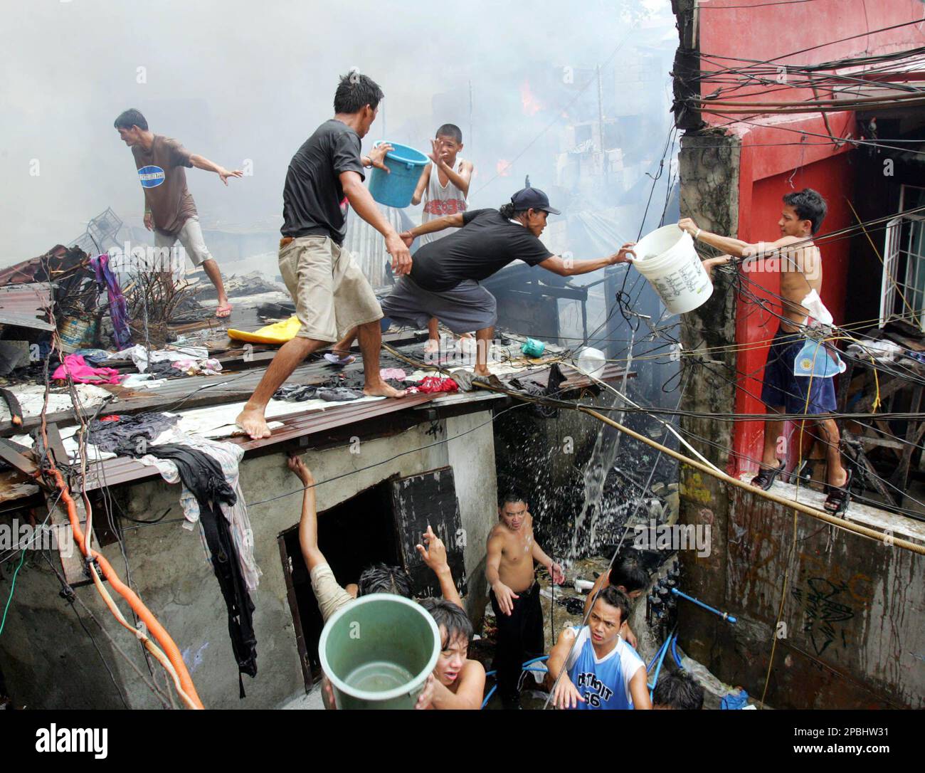 Local residents pass on pails of water as they try to put out the fire ...