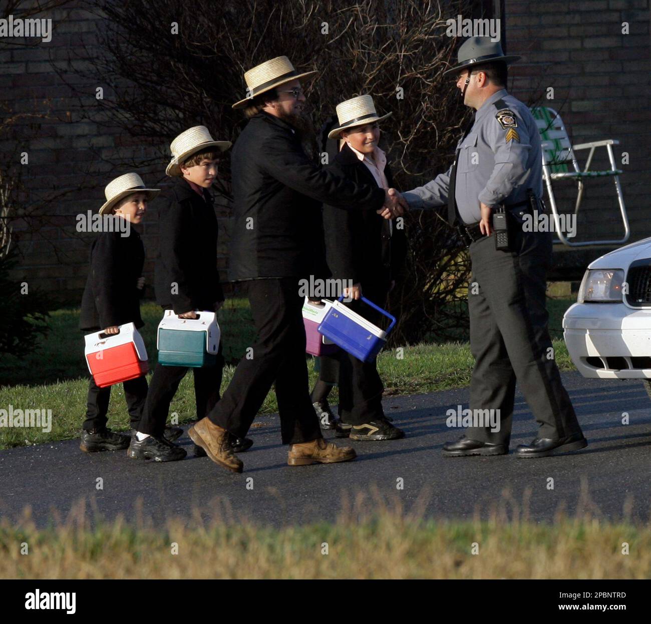 Amish children, accompanied by an adult, center, are greeted by a State ...