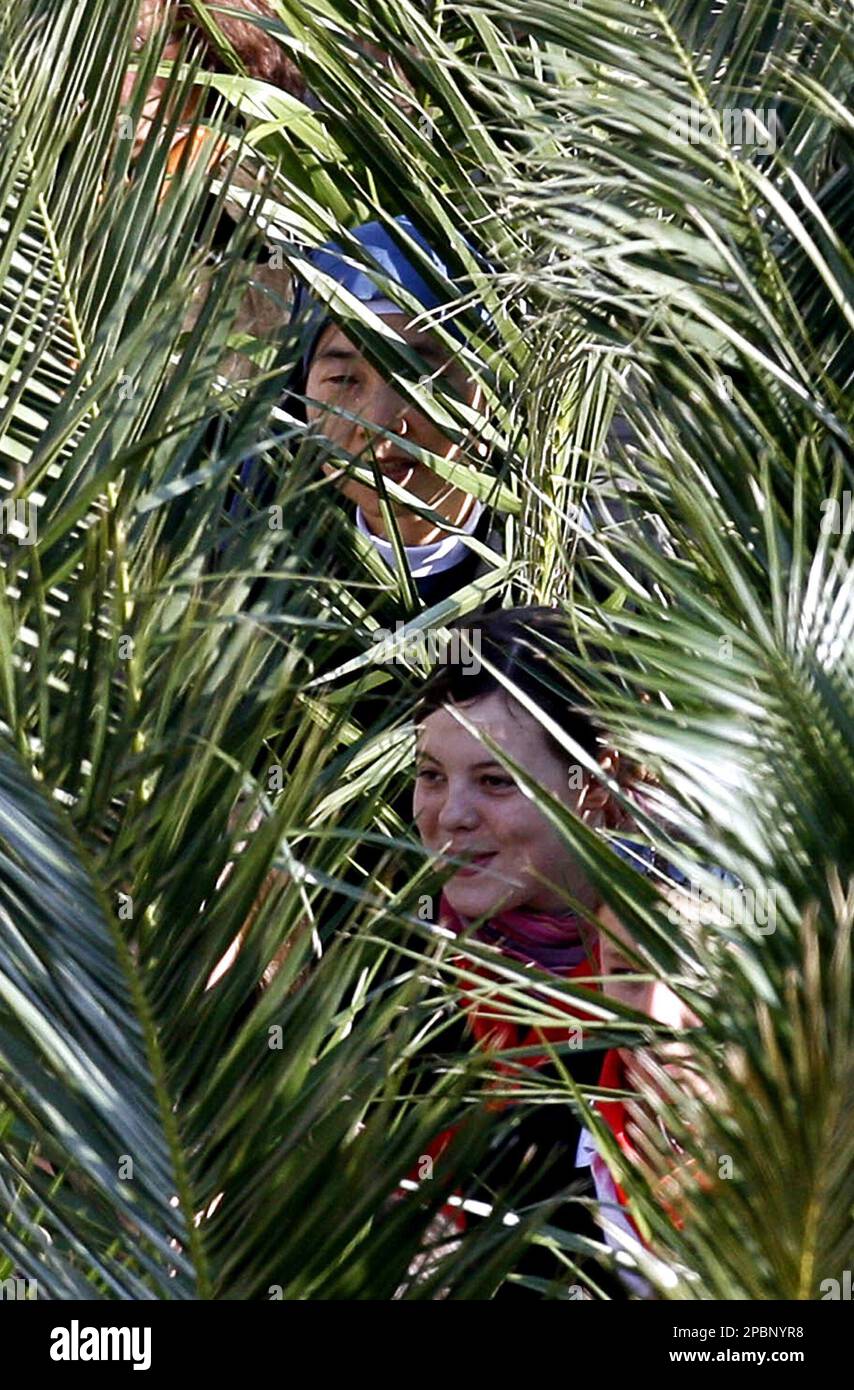 Faithful and nuns peek through branches of olive tree as they follow an ...