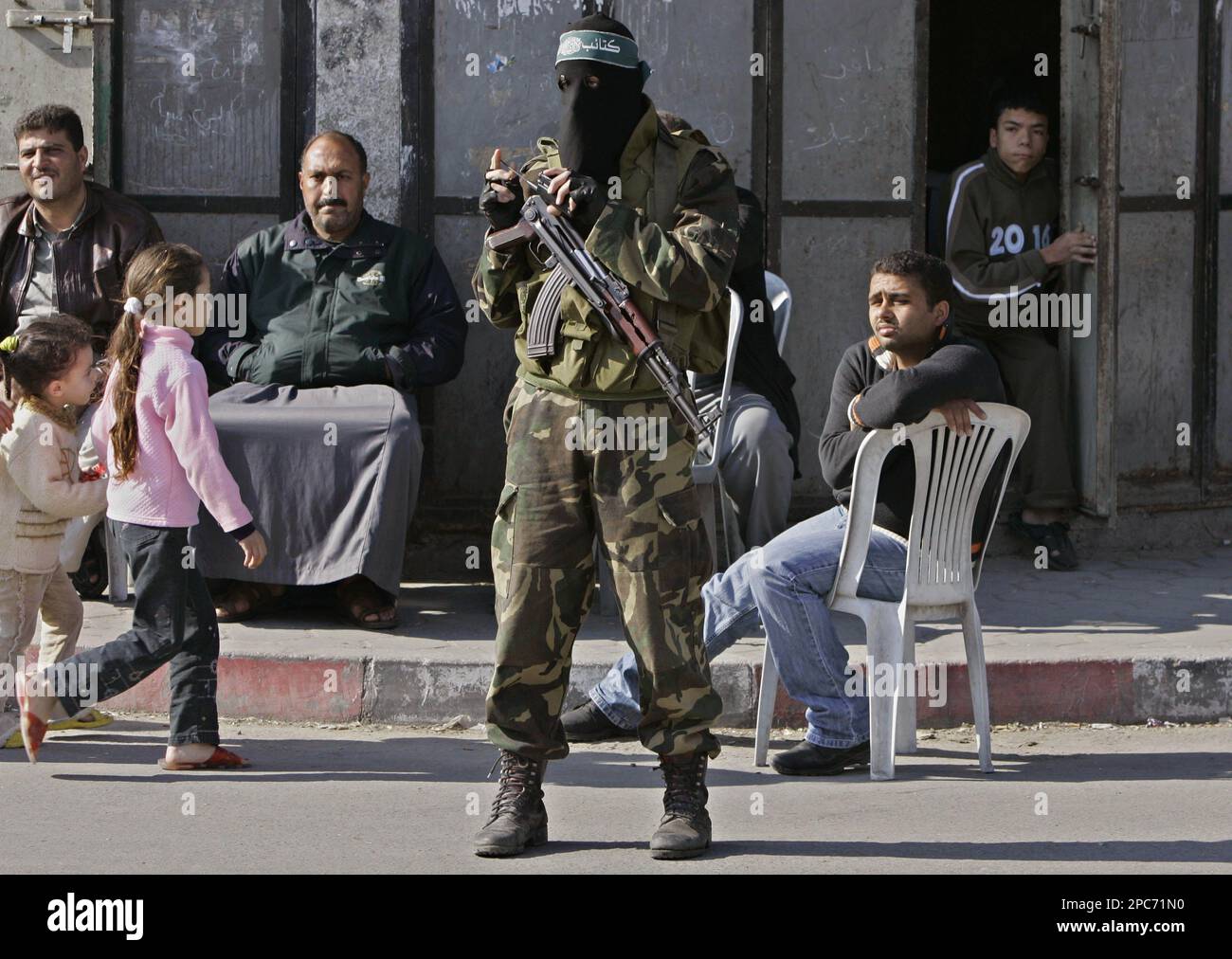 A masked Hamas militant stands next to Palestinian residents during the ...