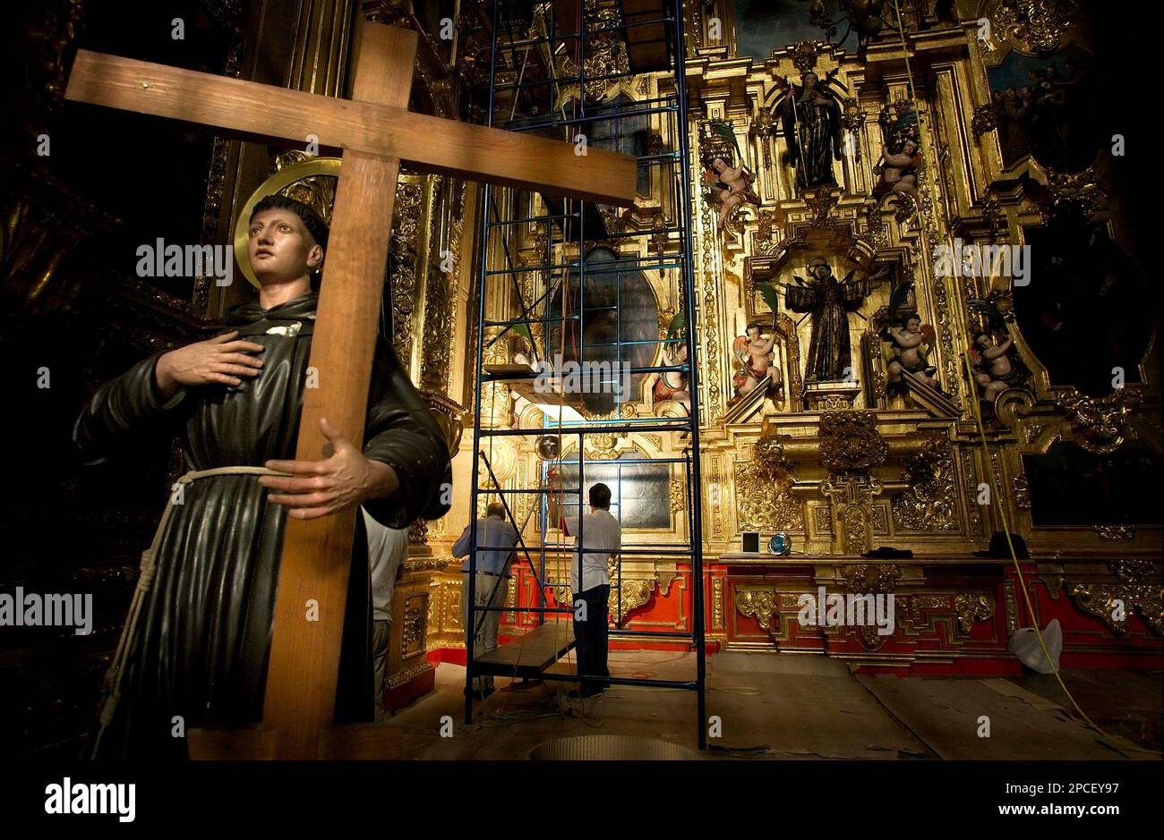 A worker illuminates part of an altar for Saint Phillip of Jesus during ...