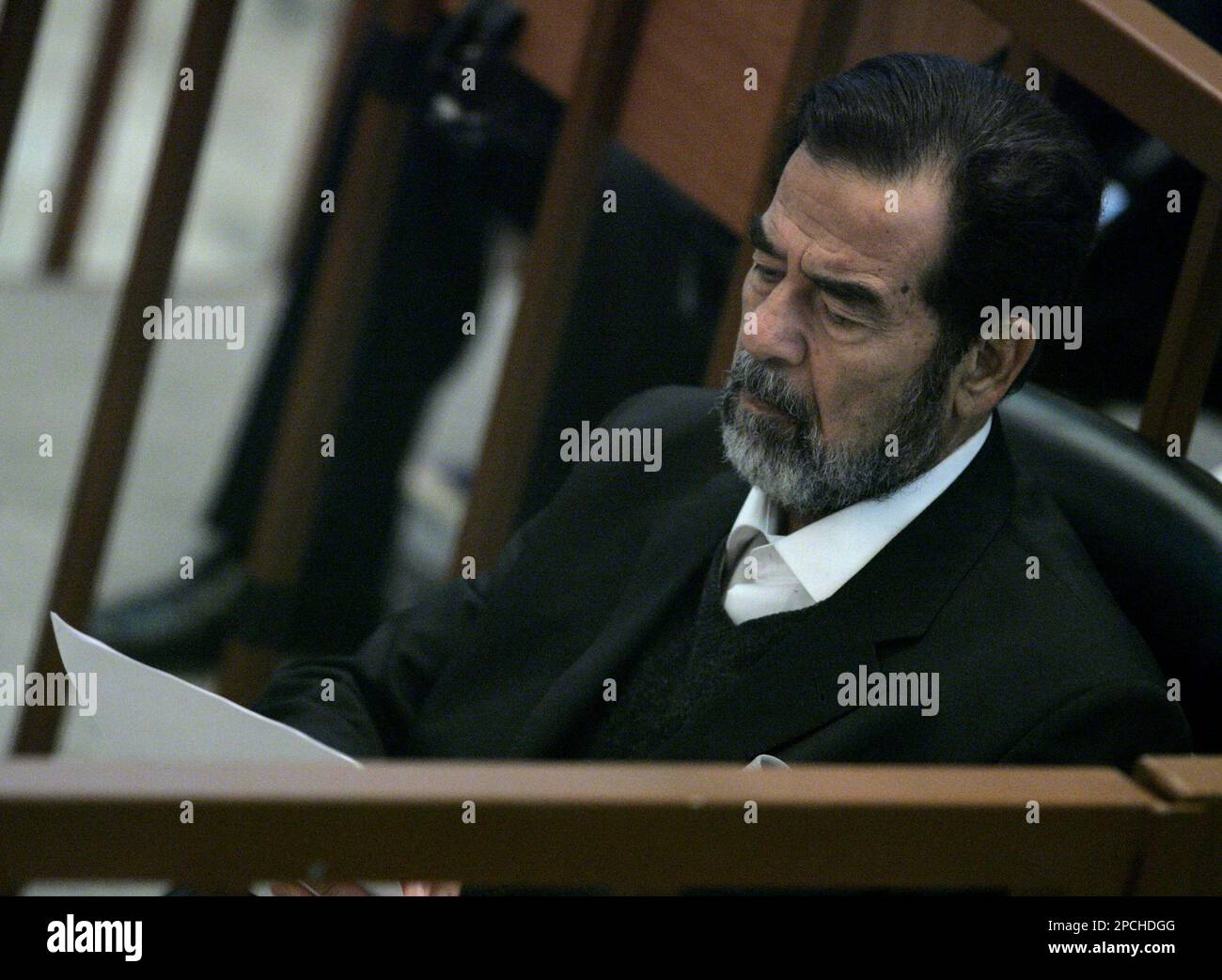 Former Iraqi president Saddam Hussein reads documents during his trial ...