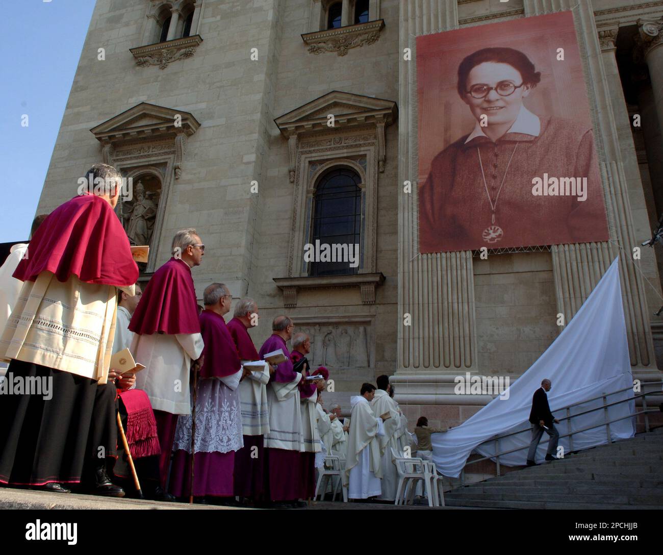 Hungarian priests look up to a giant picture showing Hungarian nun Sara ...