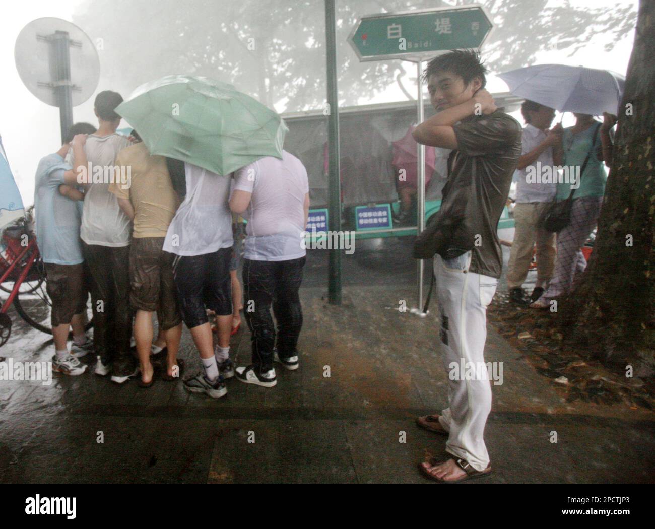 residents take shelter under a tree in Hangzhou as the city braces for ...