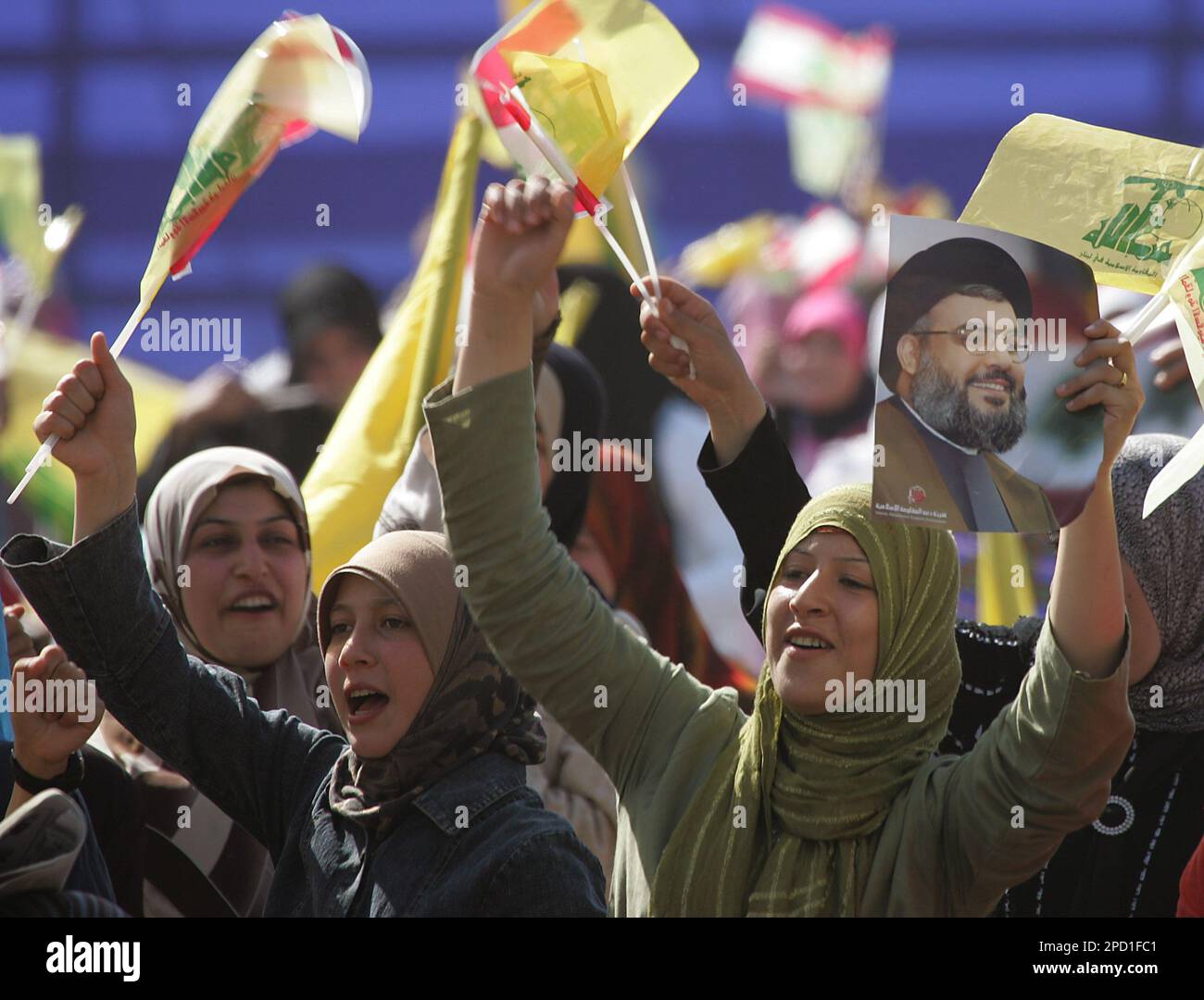 Lebanese women, wave Hezbollah flags and a poster of Hezbollah leader ...