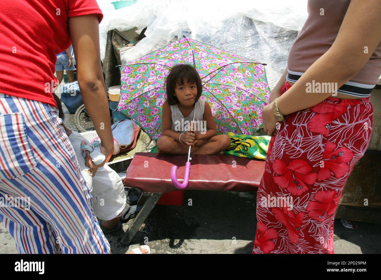 A little girl shields herself with an umbrella as her family camps out ...