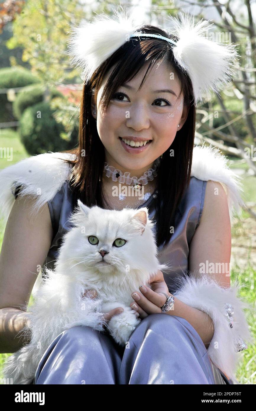 A Chinese woman dressed in a cat theme attire rest with a cat during a ...
