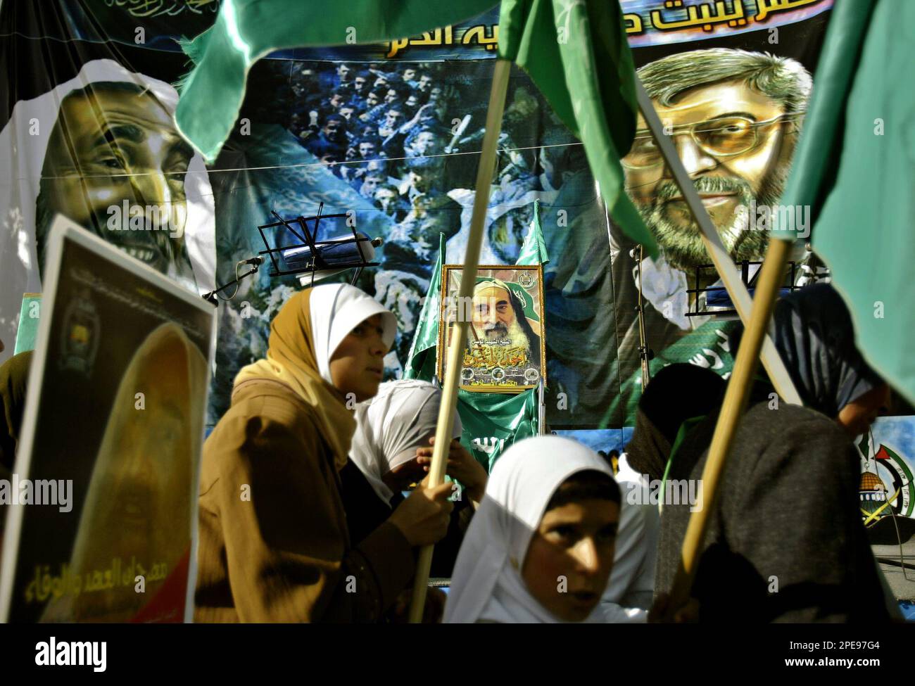 Supporters of the Palestinian Islamic group Hamas march next to banners ...