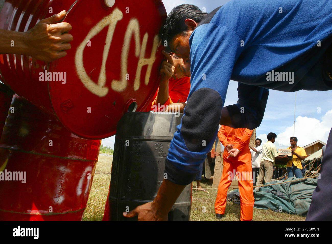 Sumatran men in the foreground transfer their currently limited supply ...