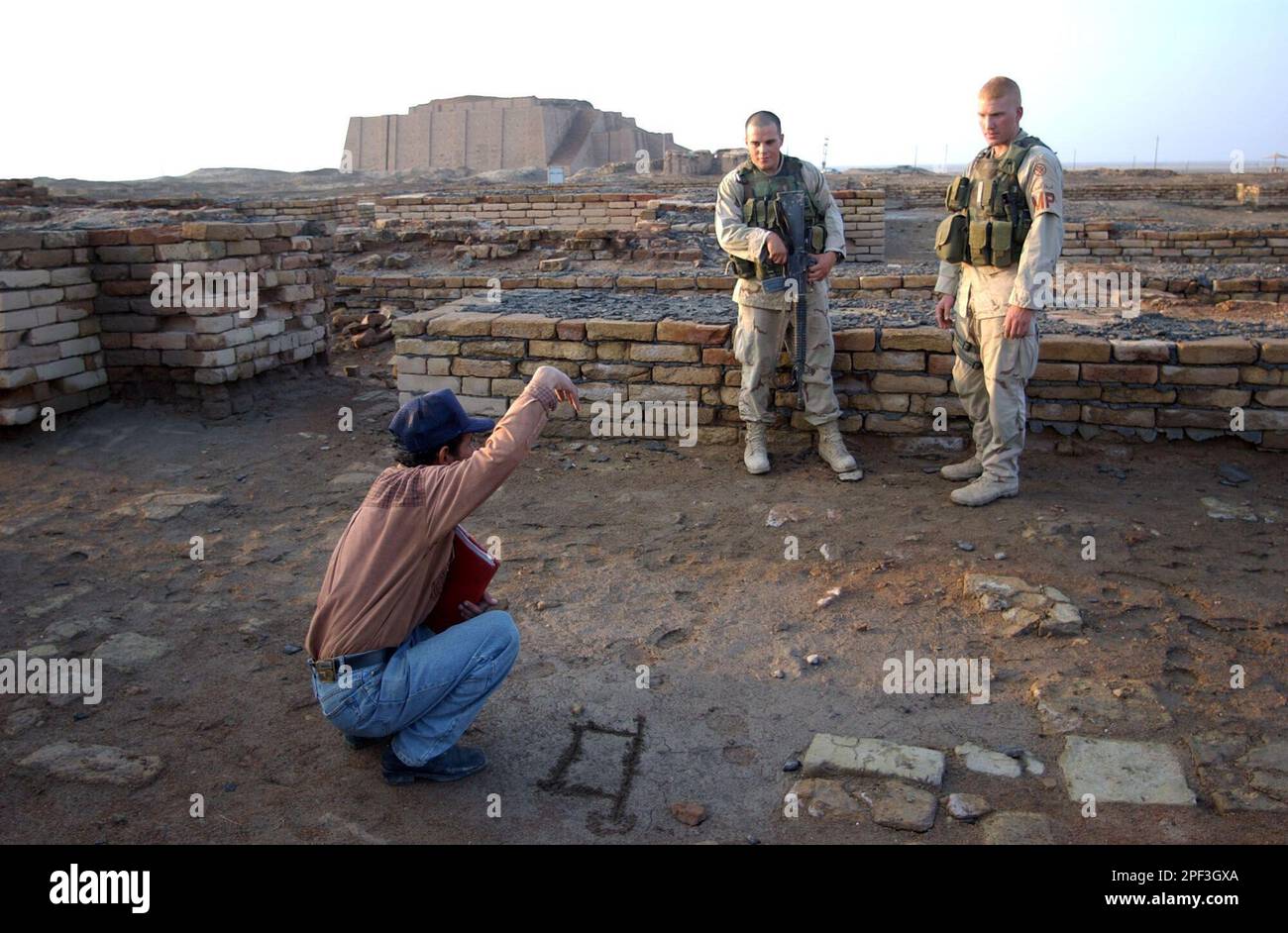 Iraqi guide Dhief Muhsen draws on the mud a map of the royal palace of ...