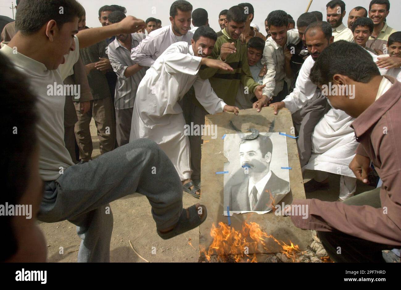 Iraqi men burn a portrait of Saddam Hussein on which they drew horns to ...