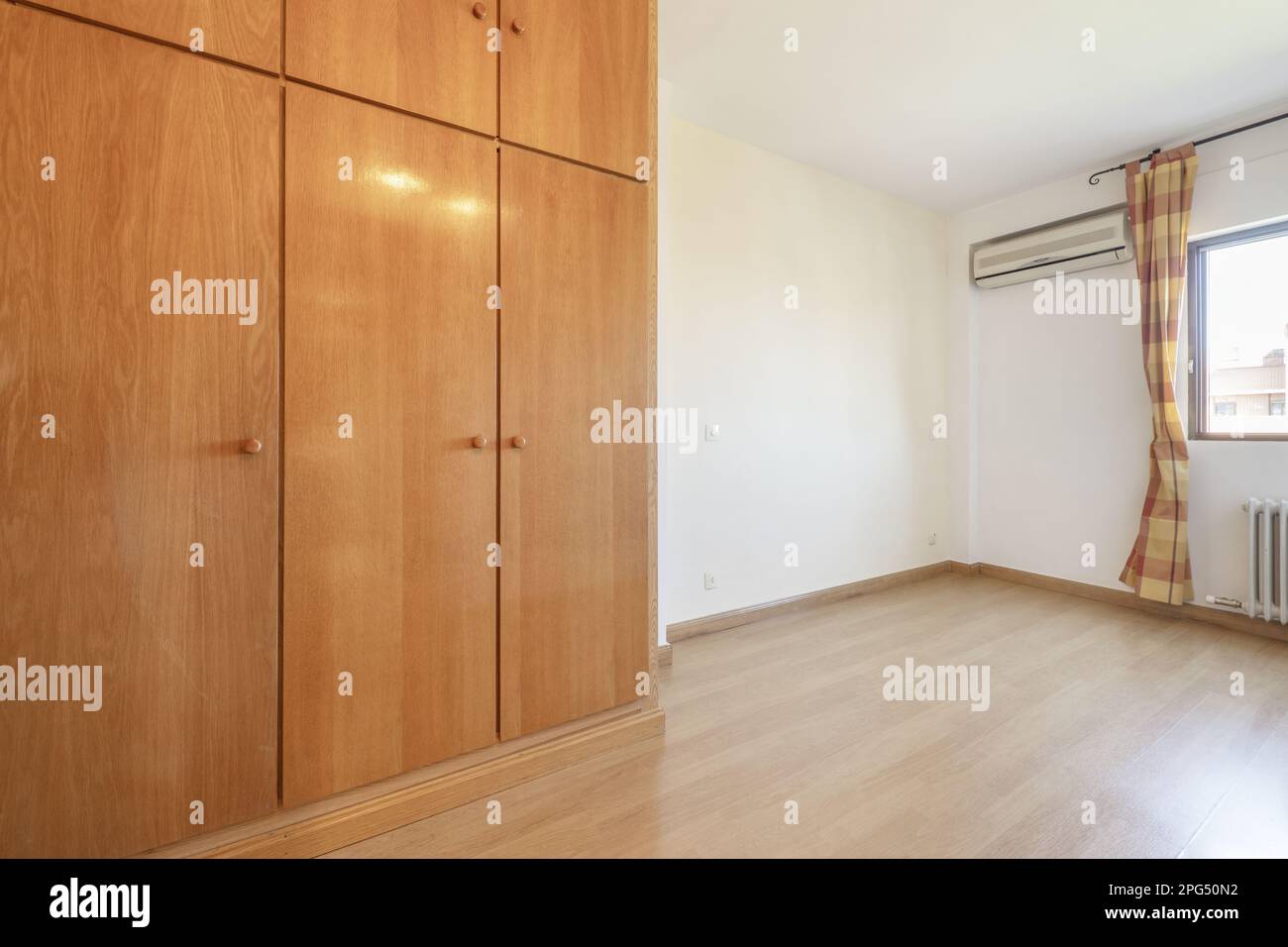 Una camera vuota con pavimento in legno marrone chiaro, un armadio a ...