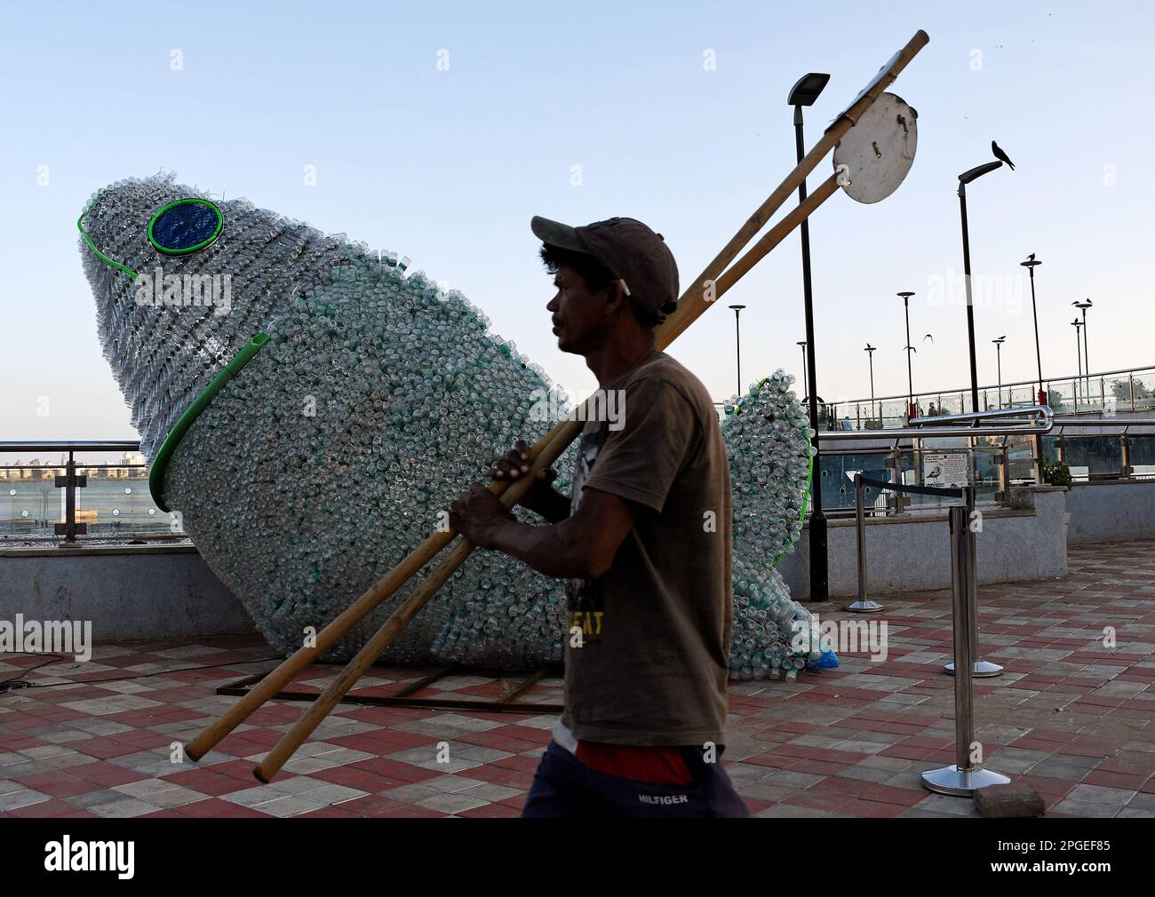 Un uomo che trasporta i remi passa accanto all'installazione di pesci ...