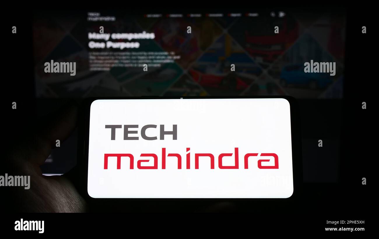 Persona che tiene il telefono cellulare con il logo della società INDIANA IT Tech Mahindra ...