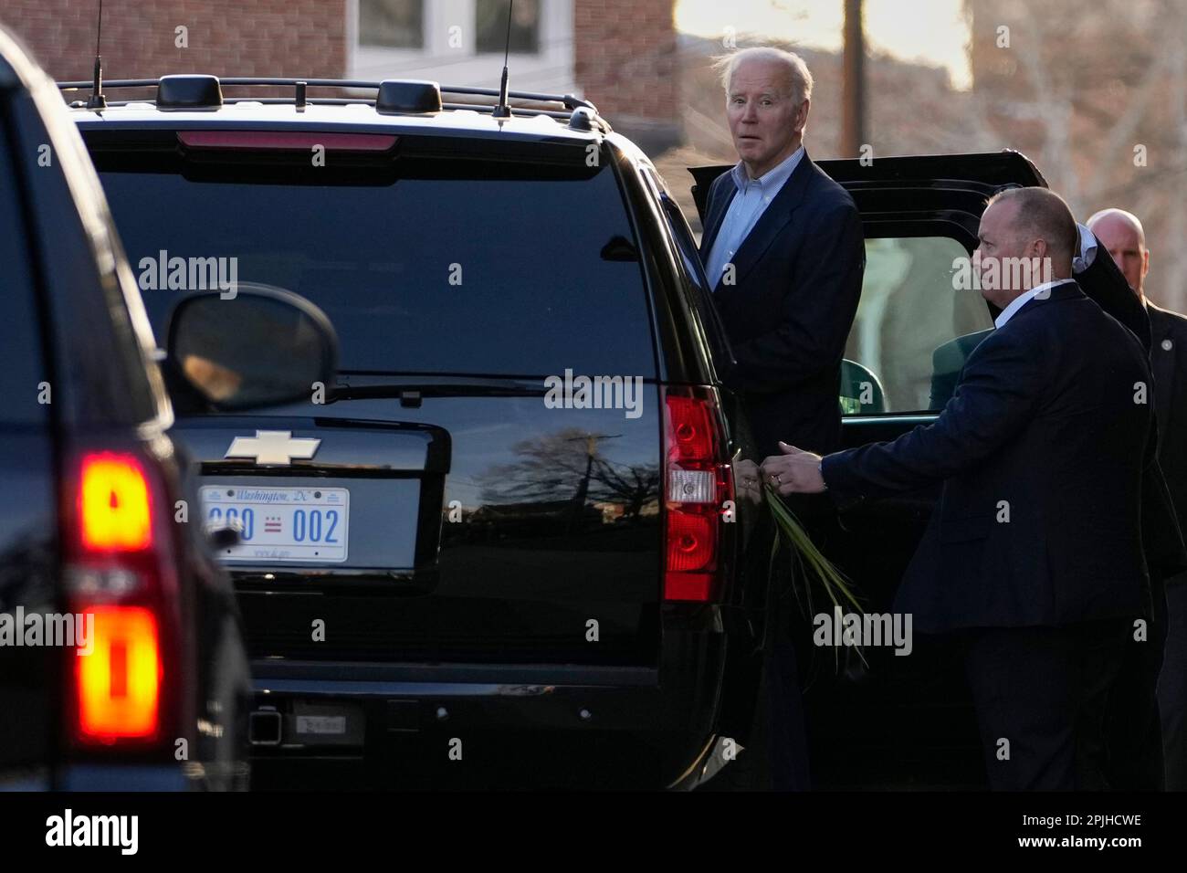 President Joe Biden looks back as he boards his motorcade vehicle to ...