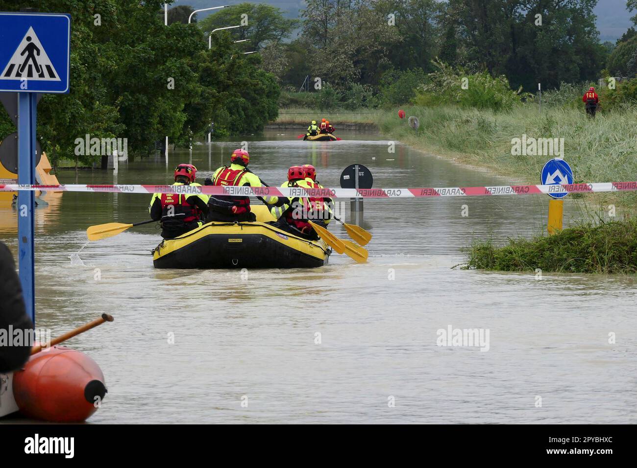 Firefighters use dinghies to cross a flooded road, near Faenza, Italy ...