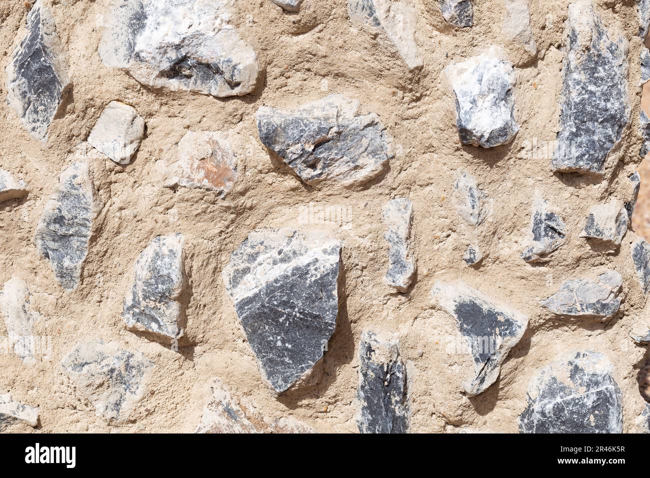 Pietre grigie mise disordinato in cemento per fare muro o strada. Trama ...