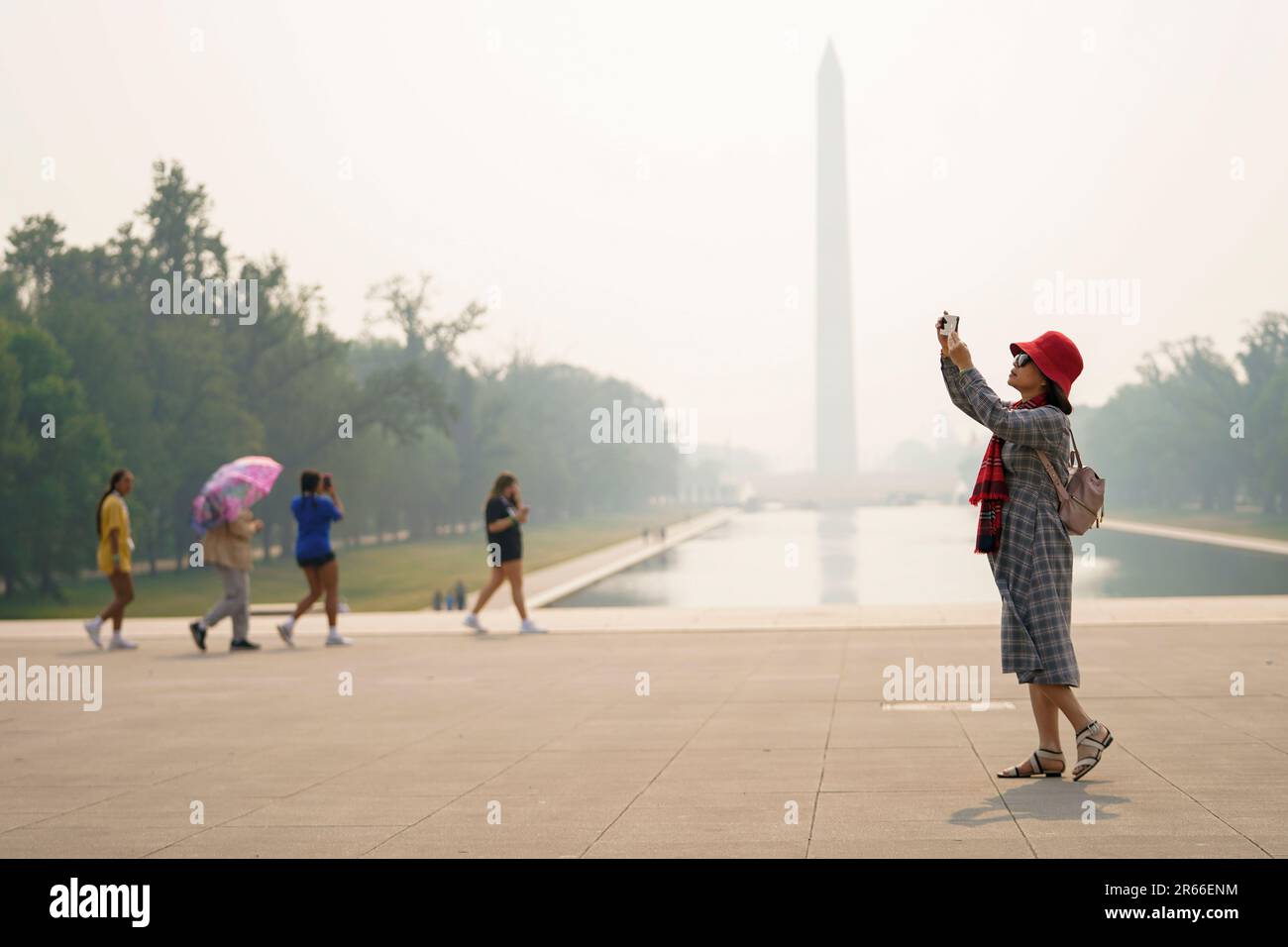 A tourist uses a cell phone to capture images as haze blankets over the ...