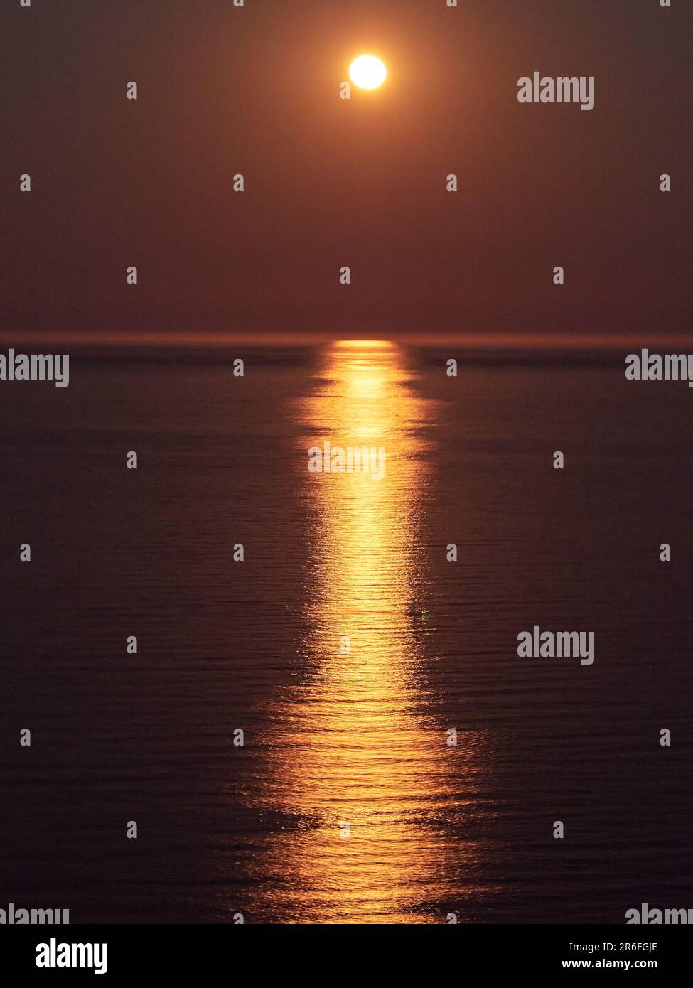 Una luna piena che riflette nel mare calmo di notte Foto stock - Alamy