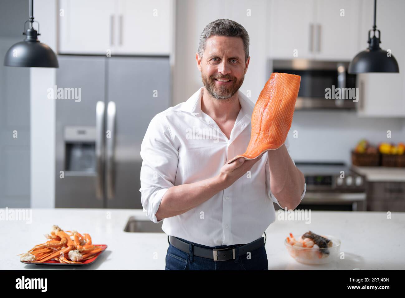 Uomo con filetto di salmone crudo in cucina. Chef che prepara un ...