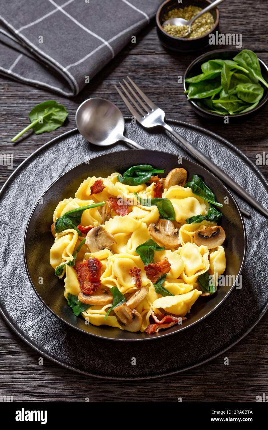 tortellini con funghi, spinaci e pancetta fritta in ciotola nera su ...